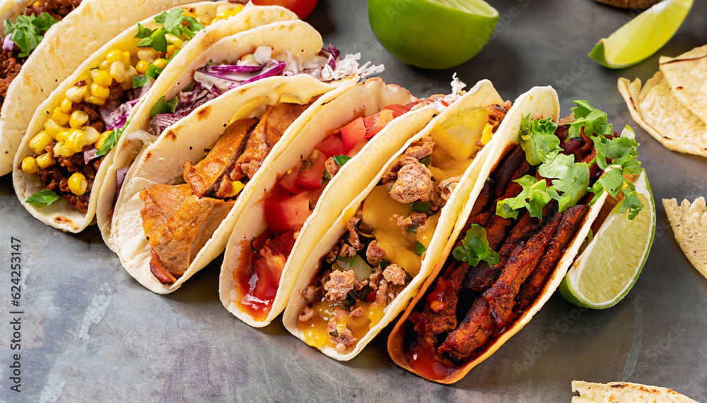 row of mexican street tacos with carne asada and al pastor in corn ...
