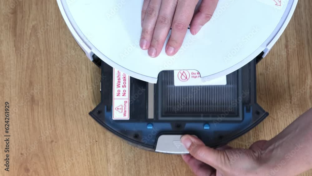 Automatic robot vacuum cleaner. Washing vacuum cleaner. A woman changes ...