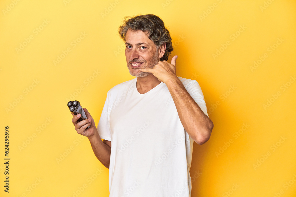 Man holding a razor, yellow studio background showing a mobile phone ...