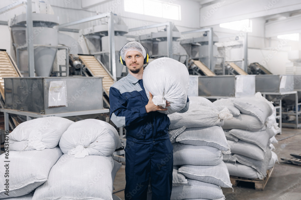 Portrait of man loader in uniform holding big bag of coffee beans or ...