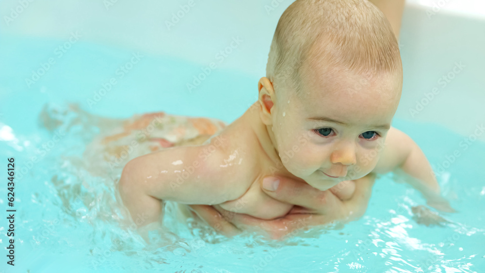 Baby girl splashes hands and kicks legs trying to swim forward in ...