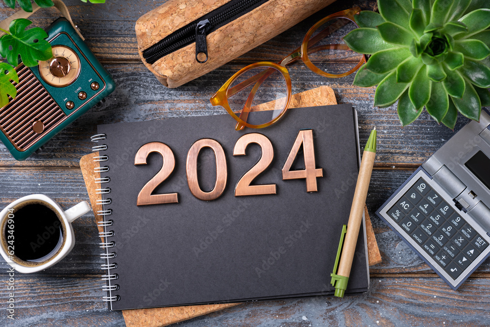 New year goals 2024 on desk. 2024 goals list with notebook, coffee cup, plant on wooden table ...