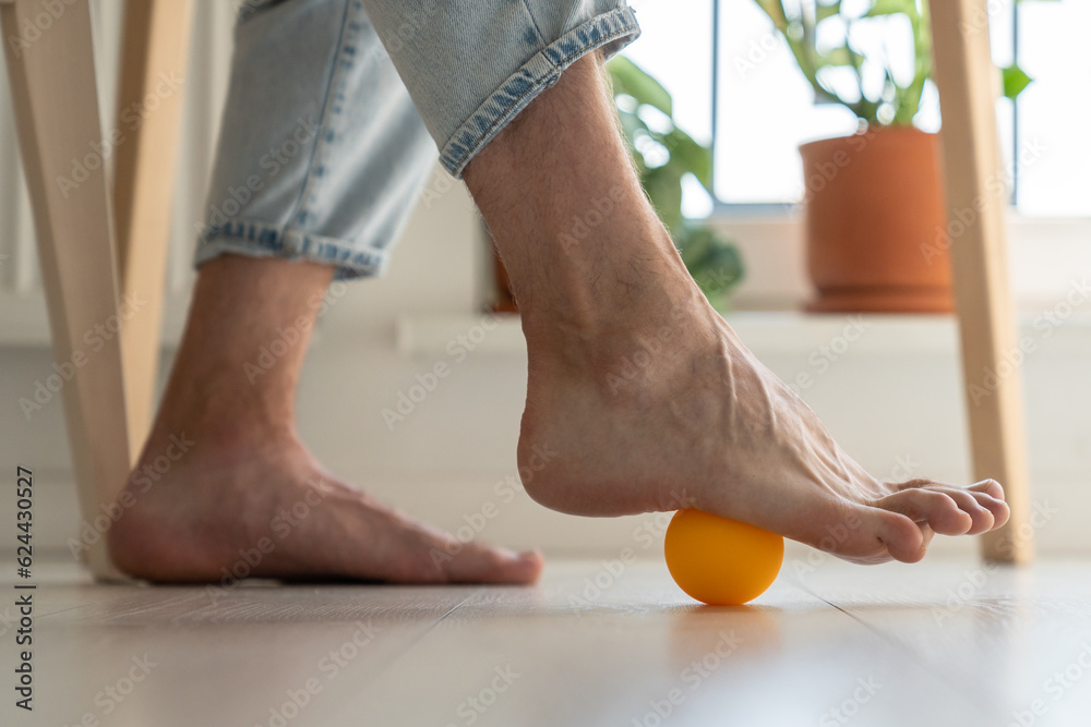 Man using silicone ball for foot massage during long sedentary work ...