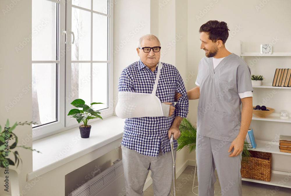 Young doctor or nurse in uniform supporting an injured senior patient ...