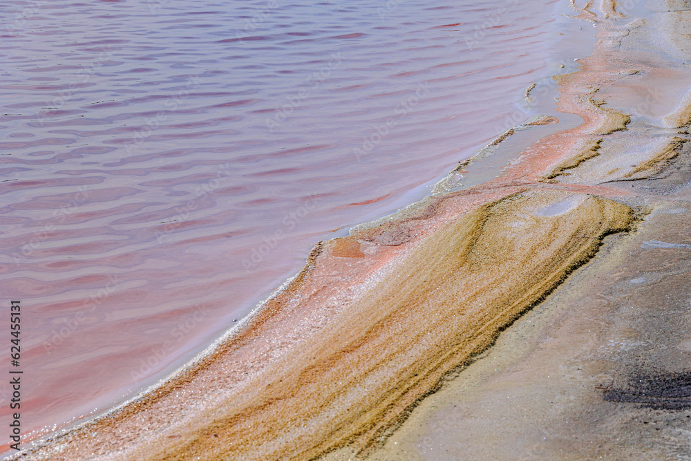 Salt-encrusted stones and pink water in the salt flats near Aigues ...