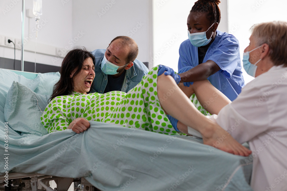 Woman giving birth to child in hospital ward receiving help from ...