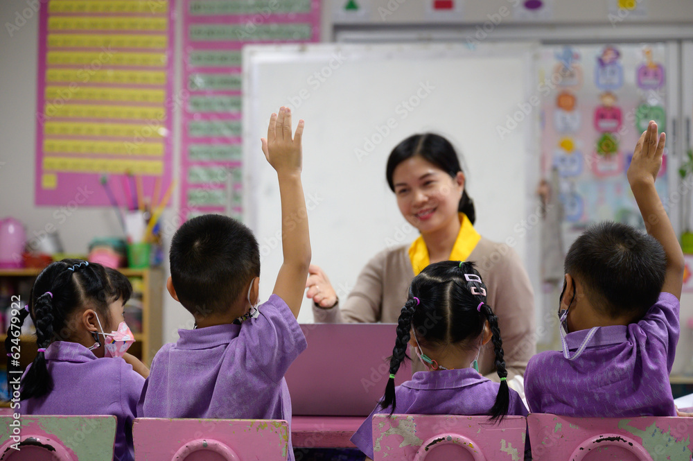 Education and school concept Asian kindergarten children raise their ...