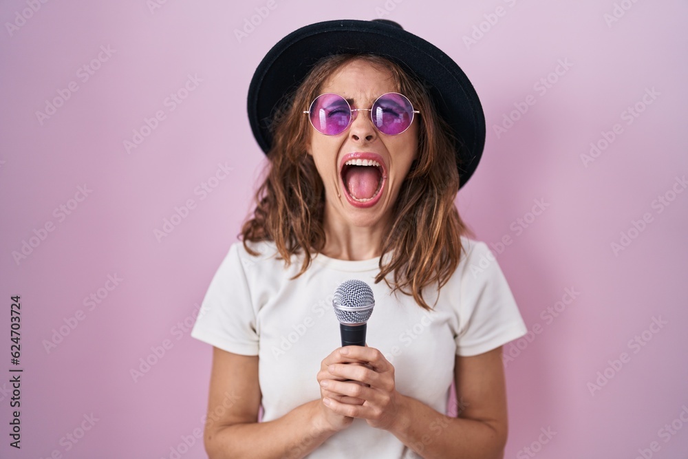 Beautiful brunette woman singing song using microphone angry and mad ...