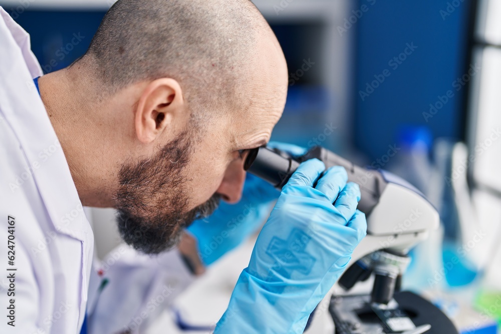 Young bald man scientist using microscope at laboratory Stock Photo ...