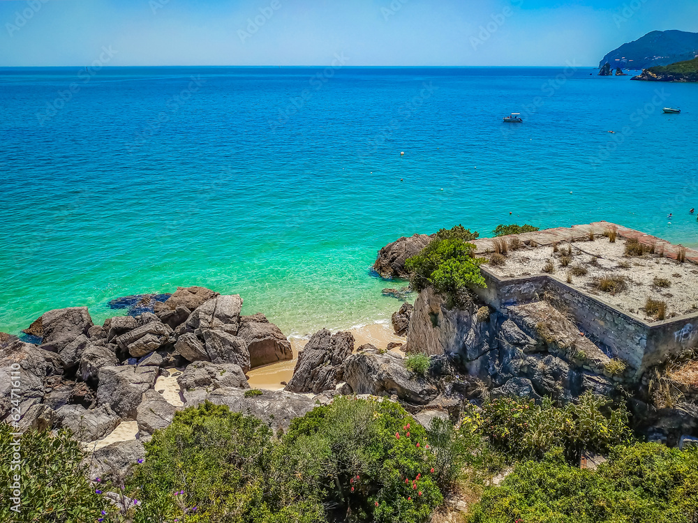 Rocks, ruins and bushes with turquoise water at Galapos Beach, Arrábida ...