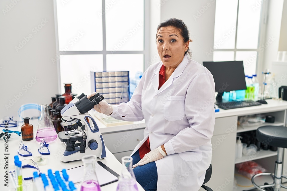 Middle age hispanic woman working at scientist laboratory scared and ...