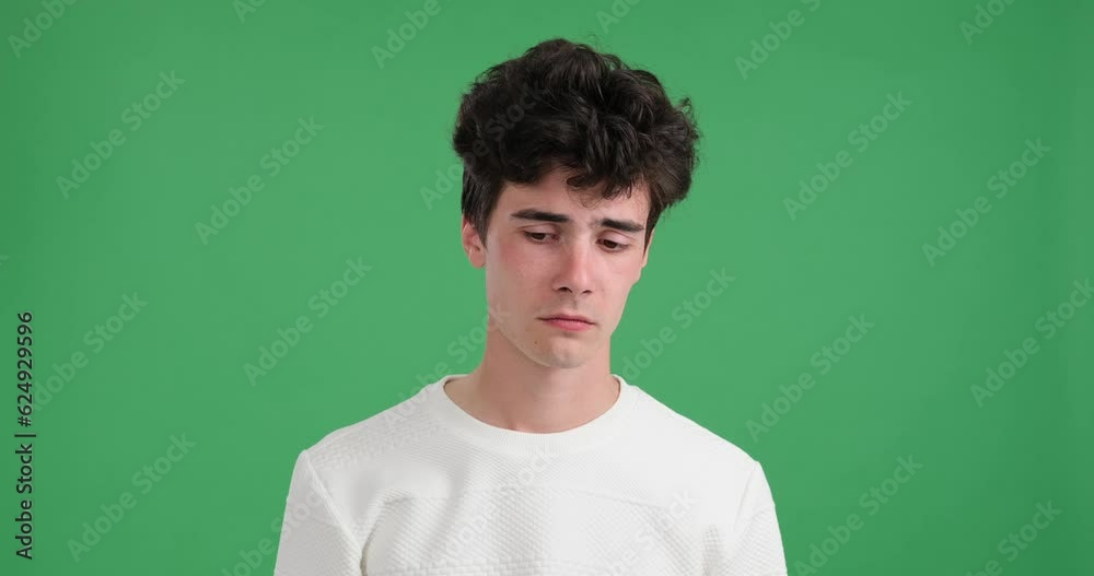 Somber Caucasian man against a vibrant green backdrop, portraying a ...