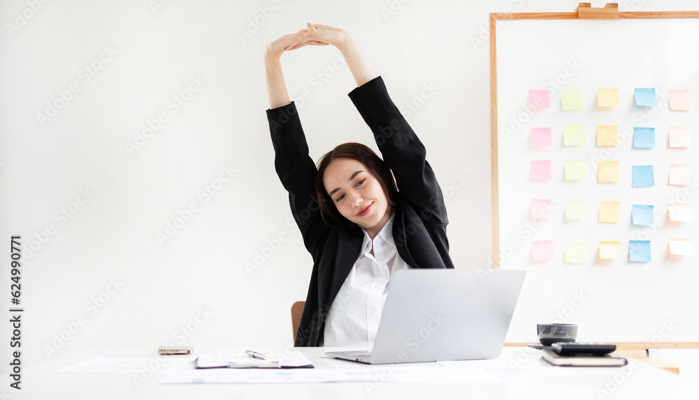 Asian female accountant is tired from working in a chair, stretching to ...