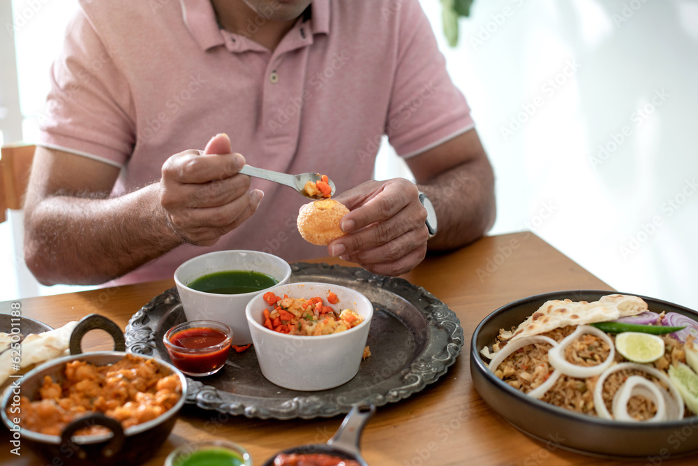 Close up, Indian man having meal at home, eating spicy Pani puri ...