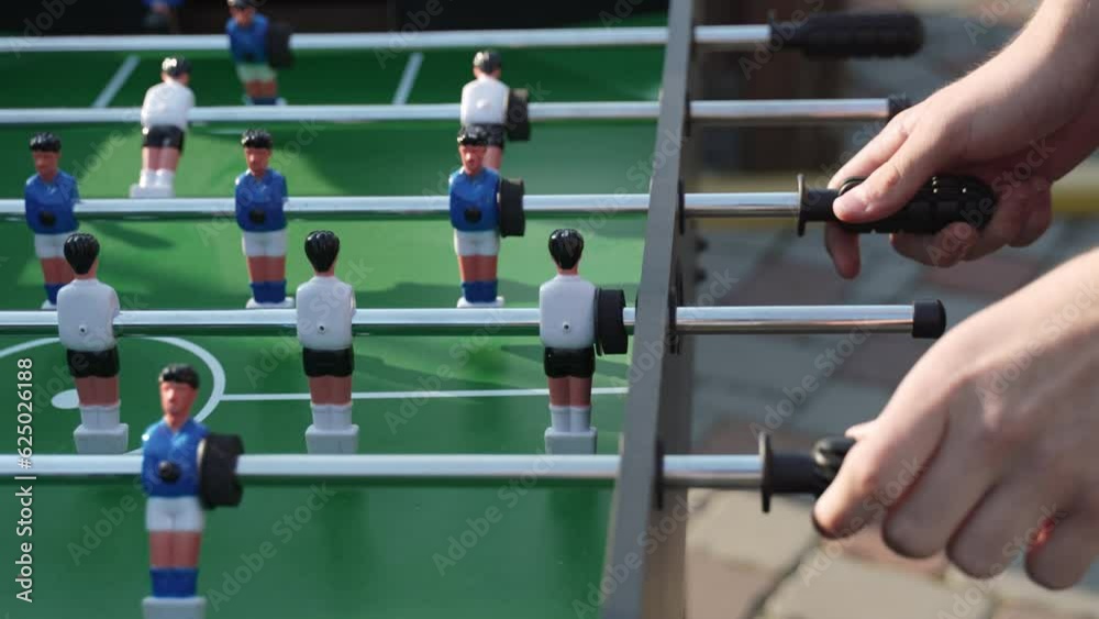 Man twists handles of axes with figurines of football players of board ...