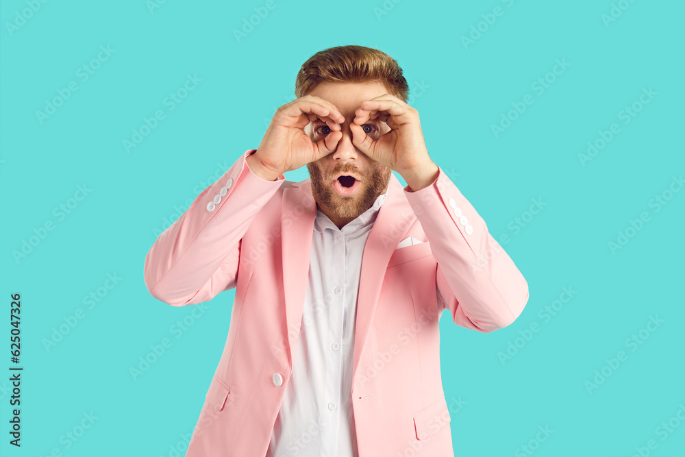 Funny man looks at something through fake, imaginary binoculars. Young ...