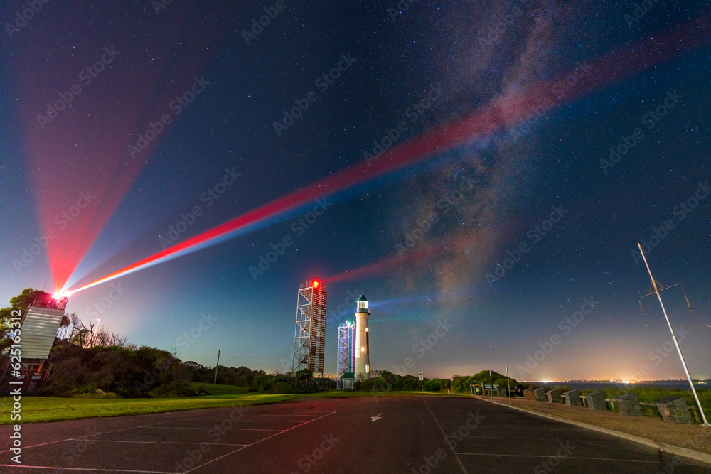 Night time scene of The Milky Way in a starry sky over a lighthouse and ...