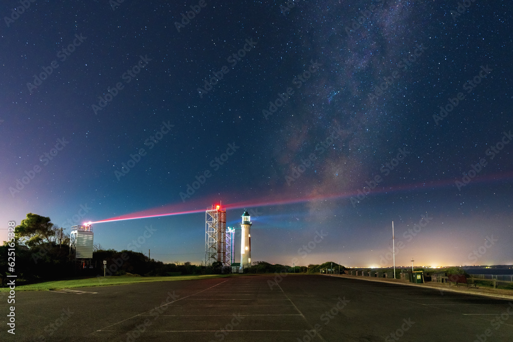 Night time scene of The Milky Way in a starry sky over a lighthouse and ...