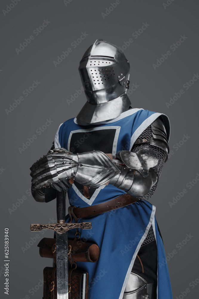 Medieval guard dressed in armor and blue surcoat holding a sword ...