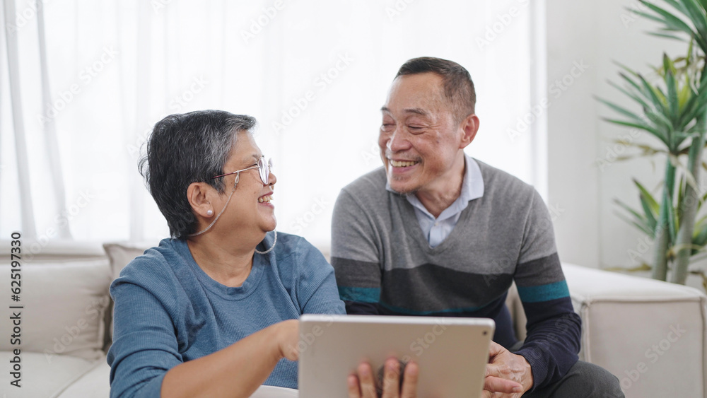 Happy elderly asian couple talking together and using tablet enjoy ...