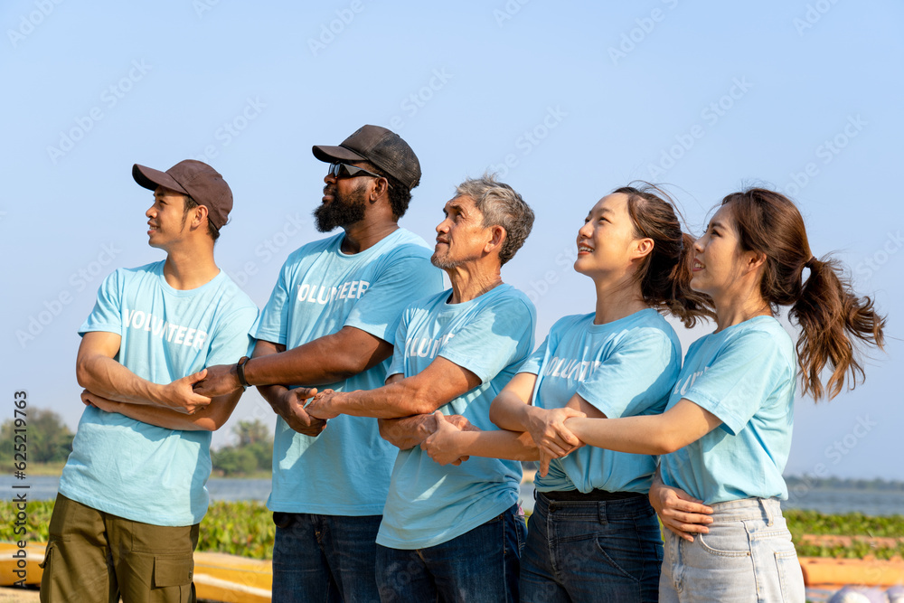 side view of volunteer team holding each other's crossed hands for ...