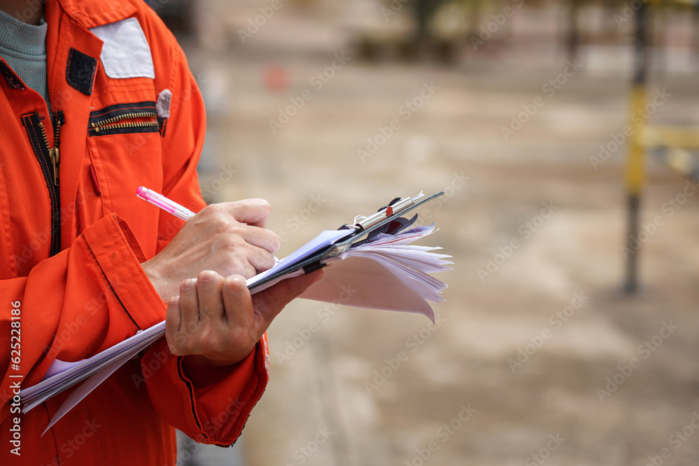 Action of a safety officer in full PPE coverall is writing note on ...