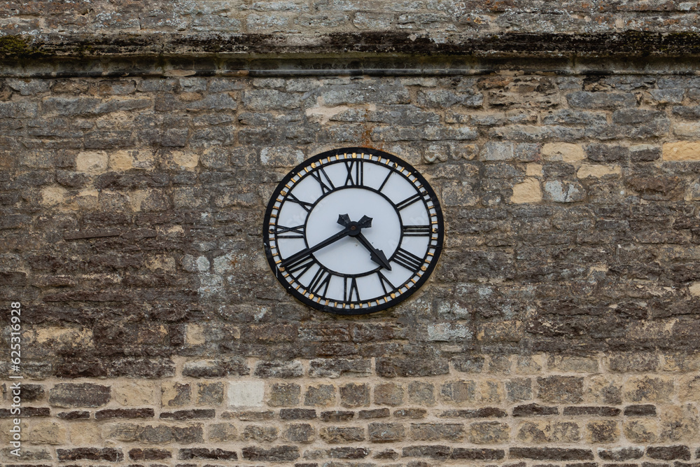 Vintage stone wall with real clock, white dial, black sword-shaped ...