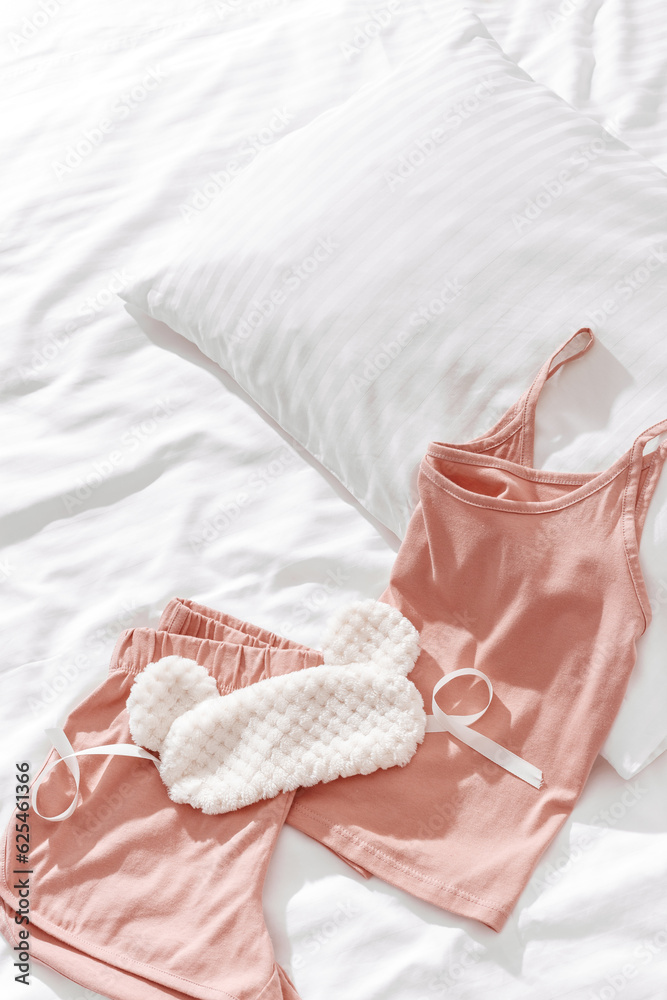 Pink woman pajamas and fluffy sleep eye mask on bed. Top view summer ...