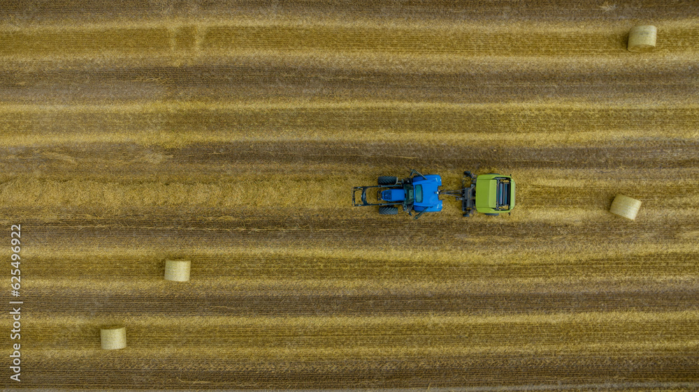 Aerial view from tractor as it pulling round baler, machine that rolls ...