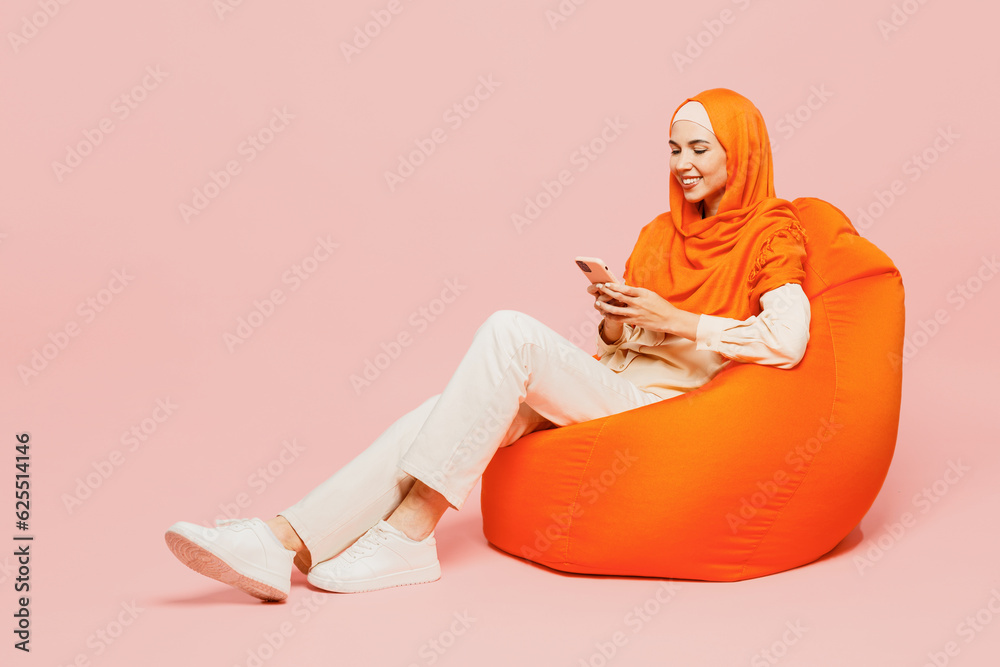 Full body young arabian asian muslim woman wears orange abaya hijab sit ...