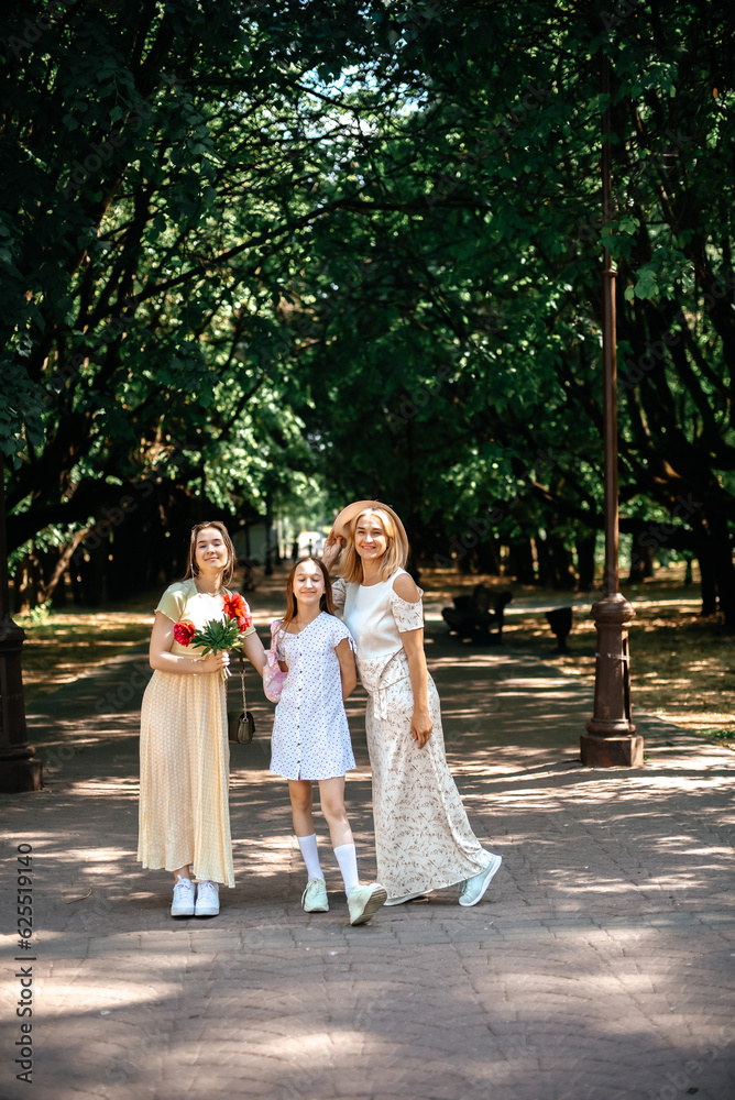Mom and two beautiful daughters walk in the summer in a green forest in ...