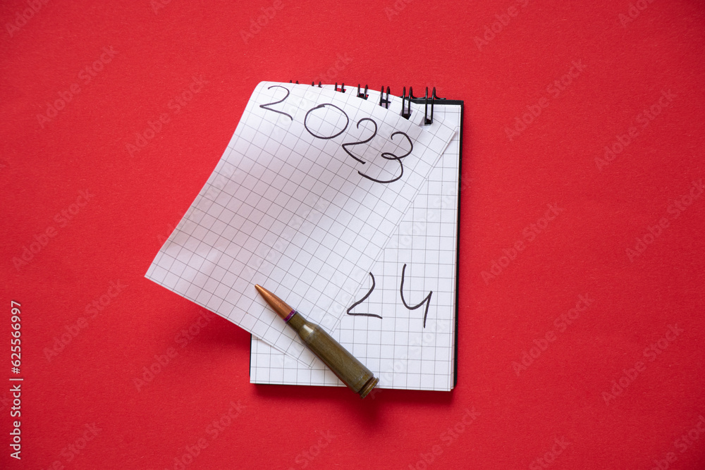 Notepad with text 2023 and 2024 and a bullet turns the page of the ...