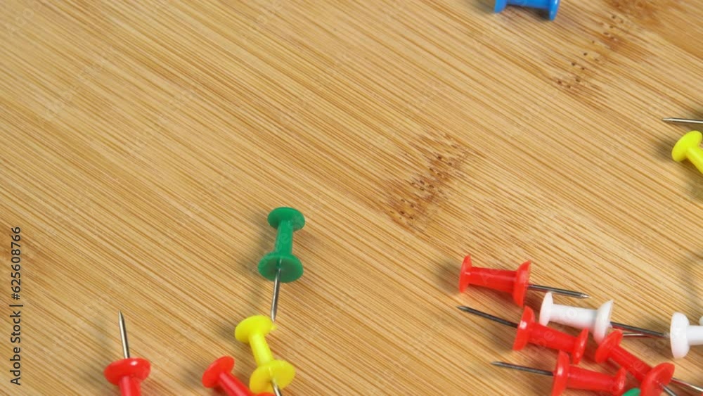 Colorful push pins falling down on the table. Drawing pins for marking ...