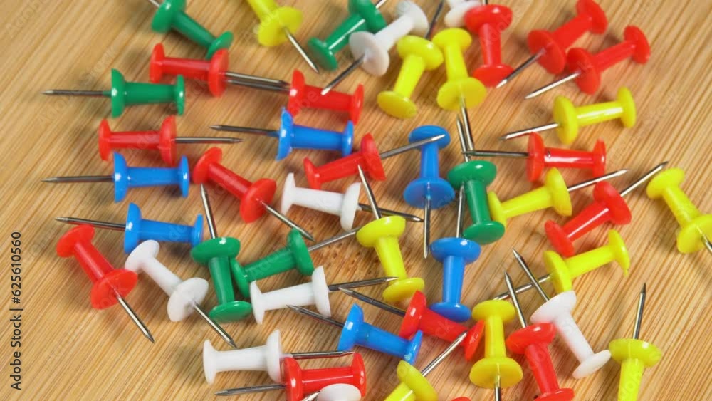 Colorful push pins rotating on the desk. Drawing pins for marking on ...
