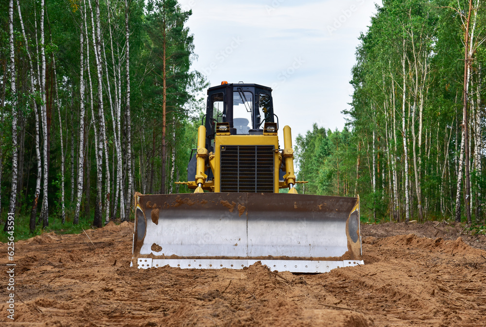 Dozer on forest clearing for road construction. Yellow Bulldozer at ...