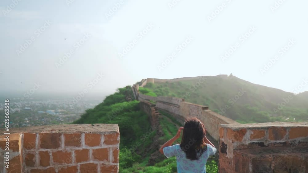 Rear view of girl walking at historical Bhujia fort wall on Bhujia ...