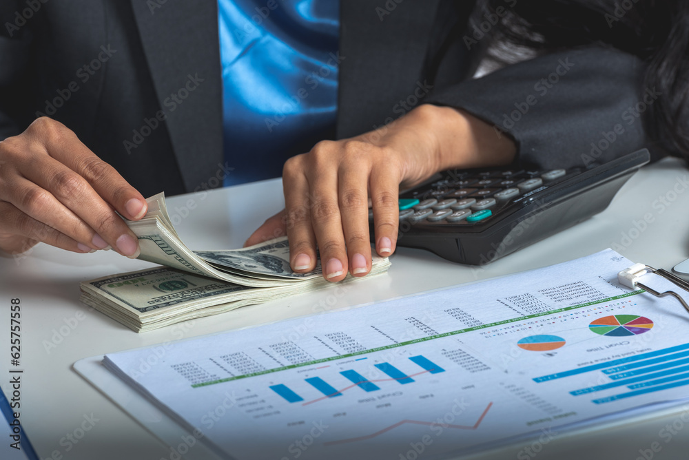accountant counting banknotes and using calculator to calculate taxes ...