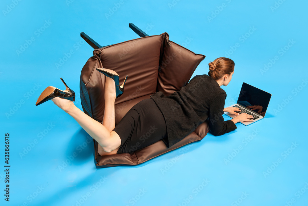 Young woman, employee lying on floor on chair in formal wear and ...