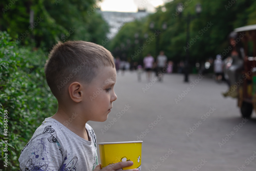 Sad young boy eating popcorn while sitting on a park bench Stock Photo ...