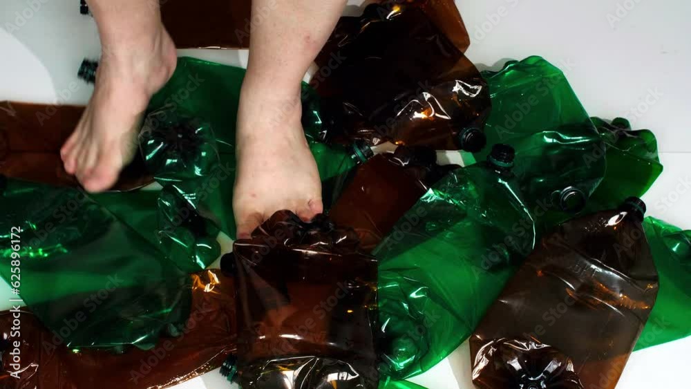 Feet trample on a lot of plastic bottles for disposal. The concept of ...