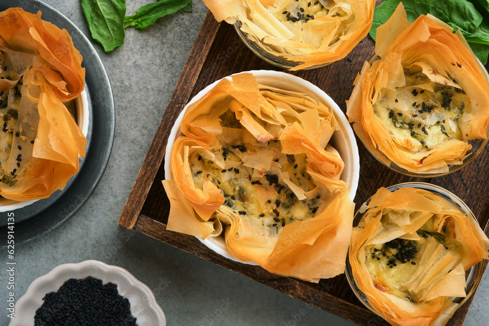 Filo pies with soft feta cheese and spinach in ceramic molds on old ...