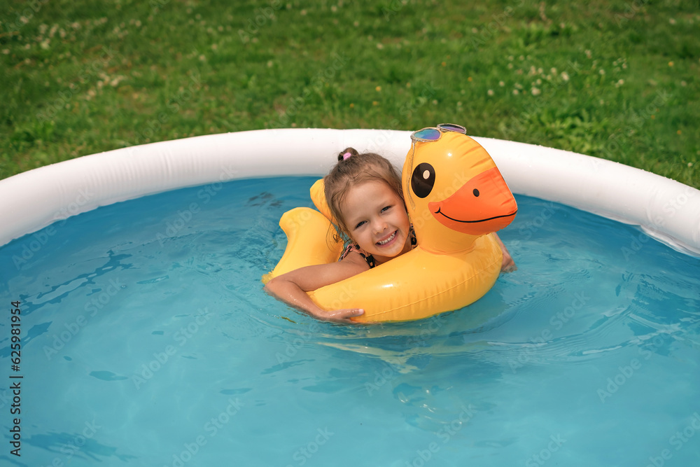 A cute child smiling looks at the camera while swimming on a circle in ...