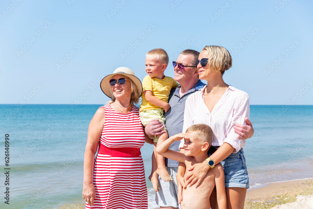 Happy family by the sea on a sunny day. Laughing grandparents, mother ...