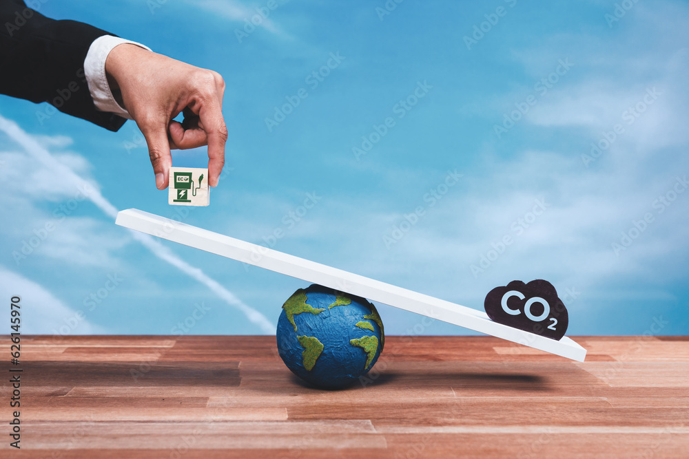 Businessman weighs EV charging station on scale against CO2 symbol ...
