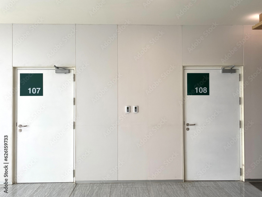2 white doors in the building and the numbers 107 and 108 on the green ...