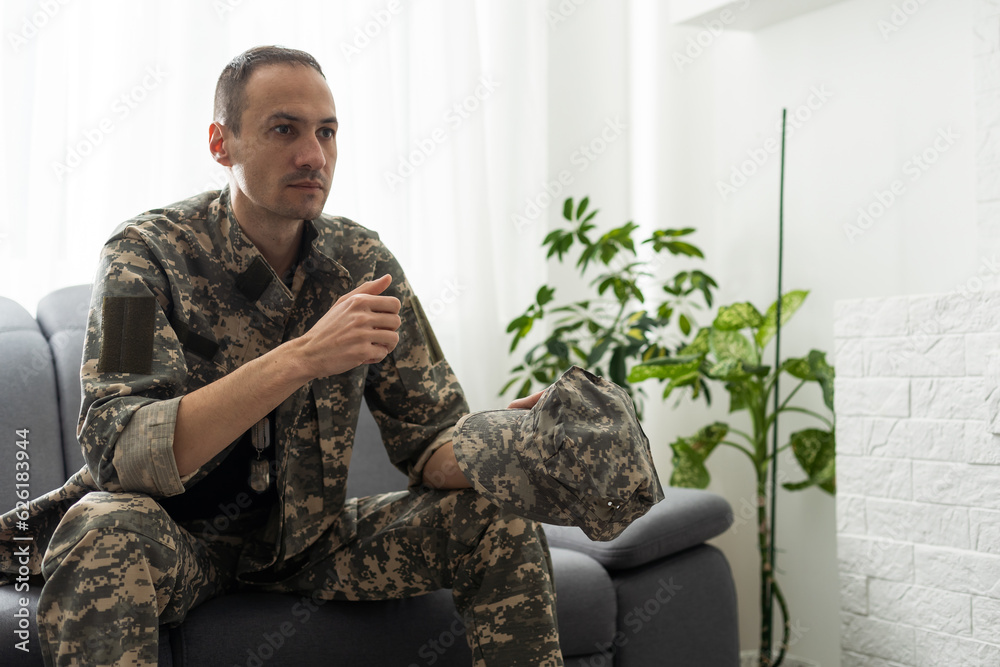 A man in a military uniform is sitting in a chair by the window ...