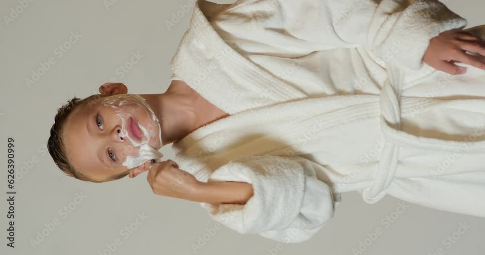 Little playful boy shaving his face cheeks isolated on grey background ...