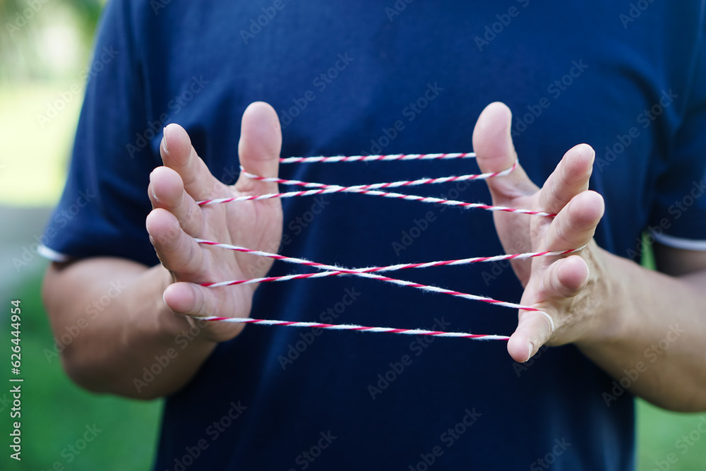 Closeup man hands is playing rope which called cats cradle game ...