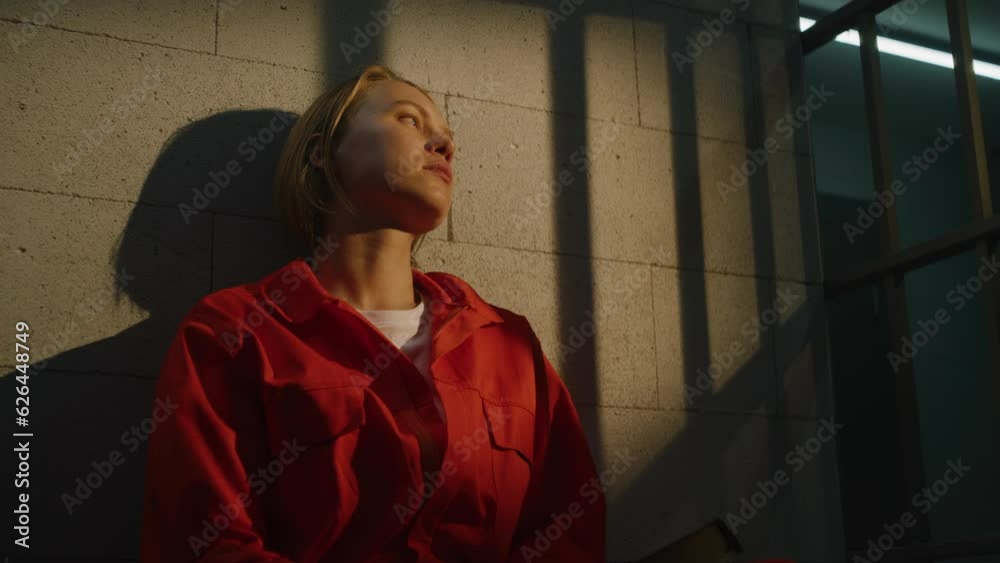 Depressed female prisoner, inmate in orange uniform sits on bed in ...
