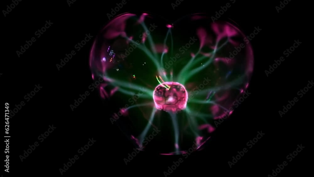 Tesla coil. Plasma globe of heart shape with green and pink light beams ...